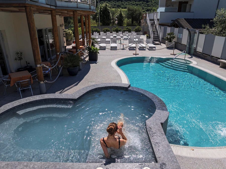 Piscina com área em formato de coração, cadeiras de descanso e área de estar coberta.