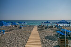 Na praia, espreguiçadeiras, guarda-sóis de praia, toalhas de praia 