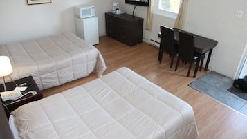 Quarto de hotel com duas camas, uma escrivaninha, televisão e uma pequena cozinha.