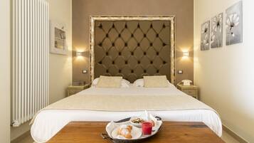 Quarto de hotel com uma cama grande, mesa de cabeceira de madeira, bandeja com itens de café da manhã e um radiador.