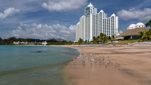 Um hotel à beira-mar com um edifício grande, uma praia e um céu claro.