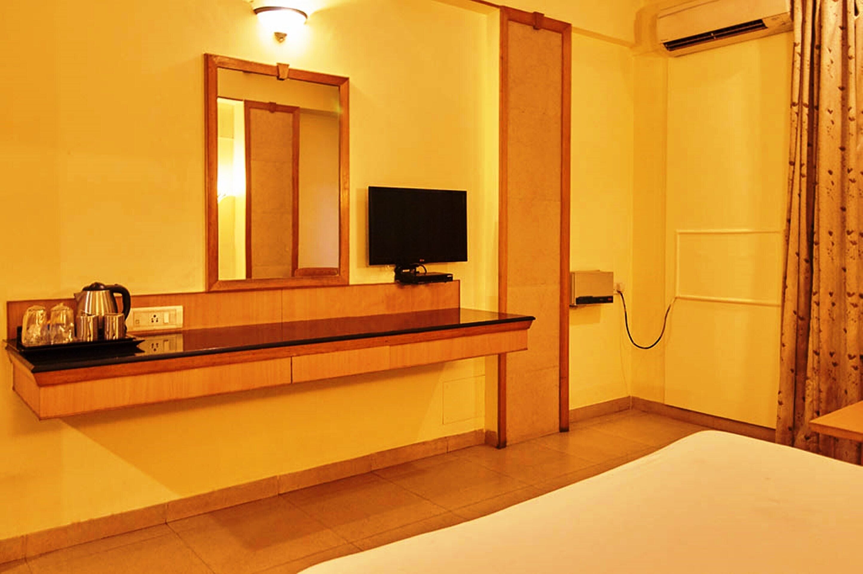 Quarto de hotel com toucador de madeira, televisão de ecrã plano, cama e área de duche.