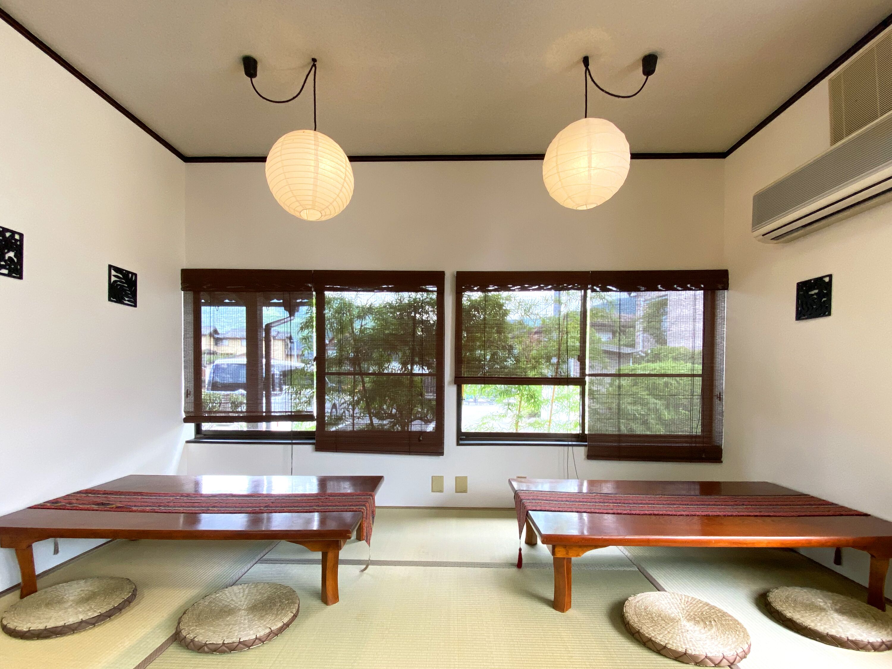 Um quarto japonês tradicional com tatames, dois tatames, uma mesa de madeira e duas lanternas de papel penduradas.