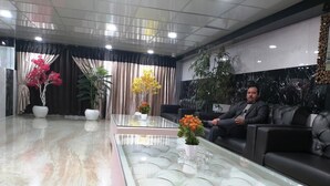Um lobby moderno com mesa de centro de vidro, sofás de couro e plantas em vasos.