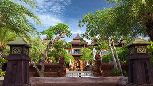 Um edifício tradicional com um pátio central, rodeado por muros de pedra e vegetação tropical.
