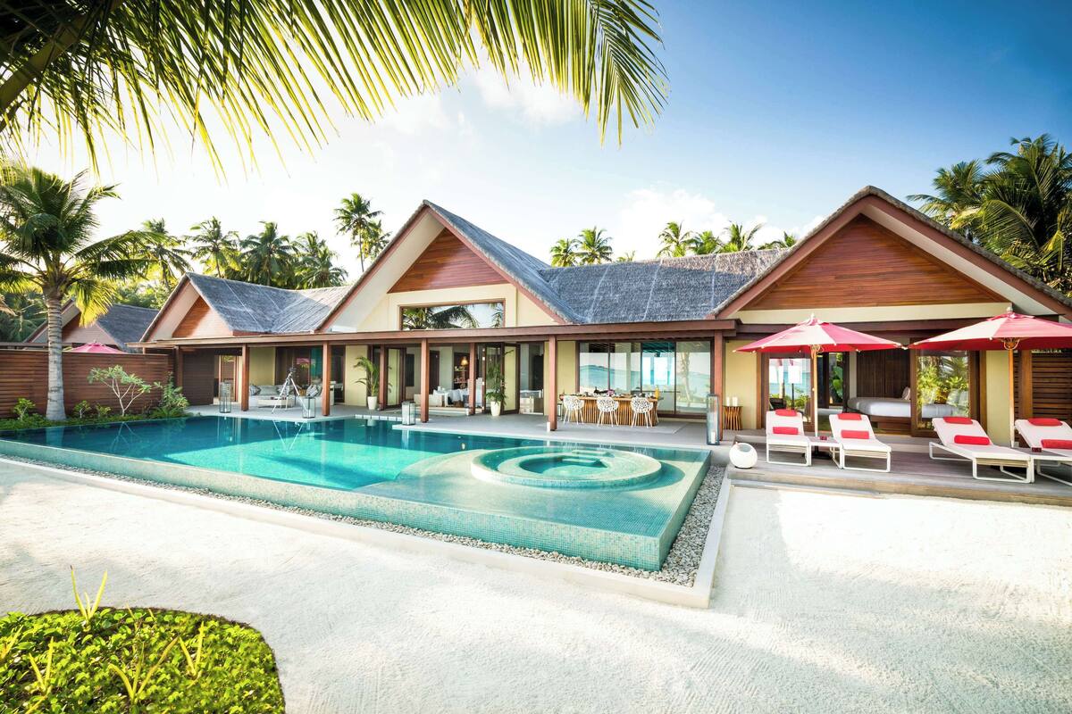 Um resort com piscina, espreguiçadeiras e palmeiras.