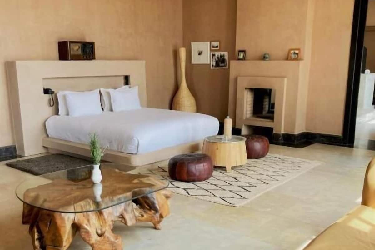Quarto de hotel moderno com uma cama grande, uma mesa de centro de madeira e um sofá de couro.