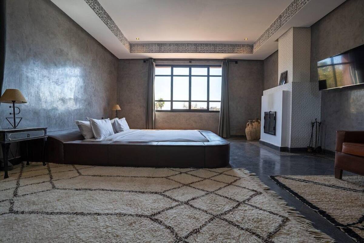 Quarto moderno com uma cama grande, uma televisão e vista para a cidade.