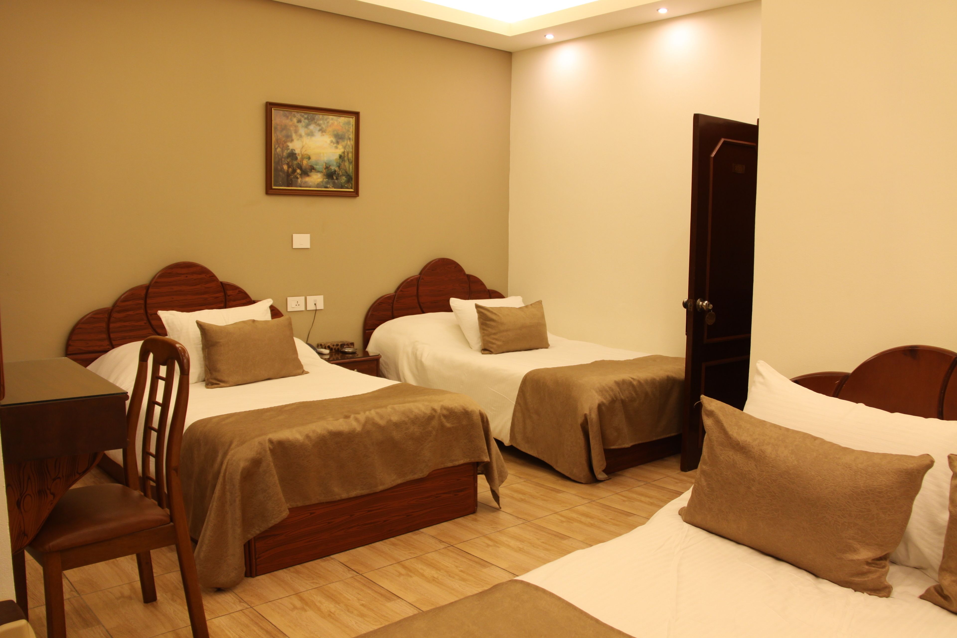 Quarto de hotel com duas camas, uma escrivaninha e uma cadeira.