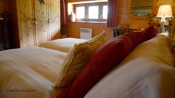 Quarto de cabana de madeira com cama, guarda-roupa e janela com cortinas.