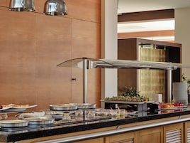 Uma mesa de buffet com diversos alimentos e um expositor de vidro.