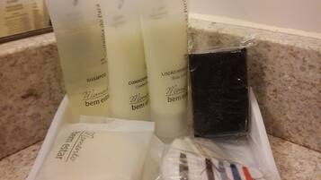 Uma bancada de banheiro com artigos de higiene pessoal, incluindo shampoo, condicionador, loção corporal e um sabonete.