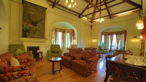 Uma sala de estar ampla com lareira, vários espaços de estar e um candelabro.