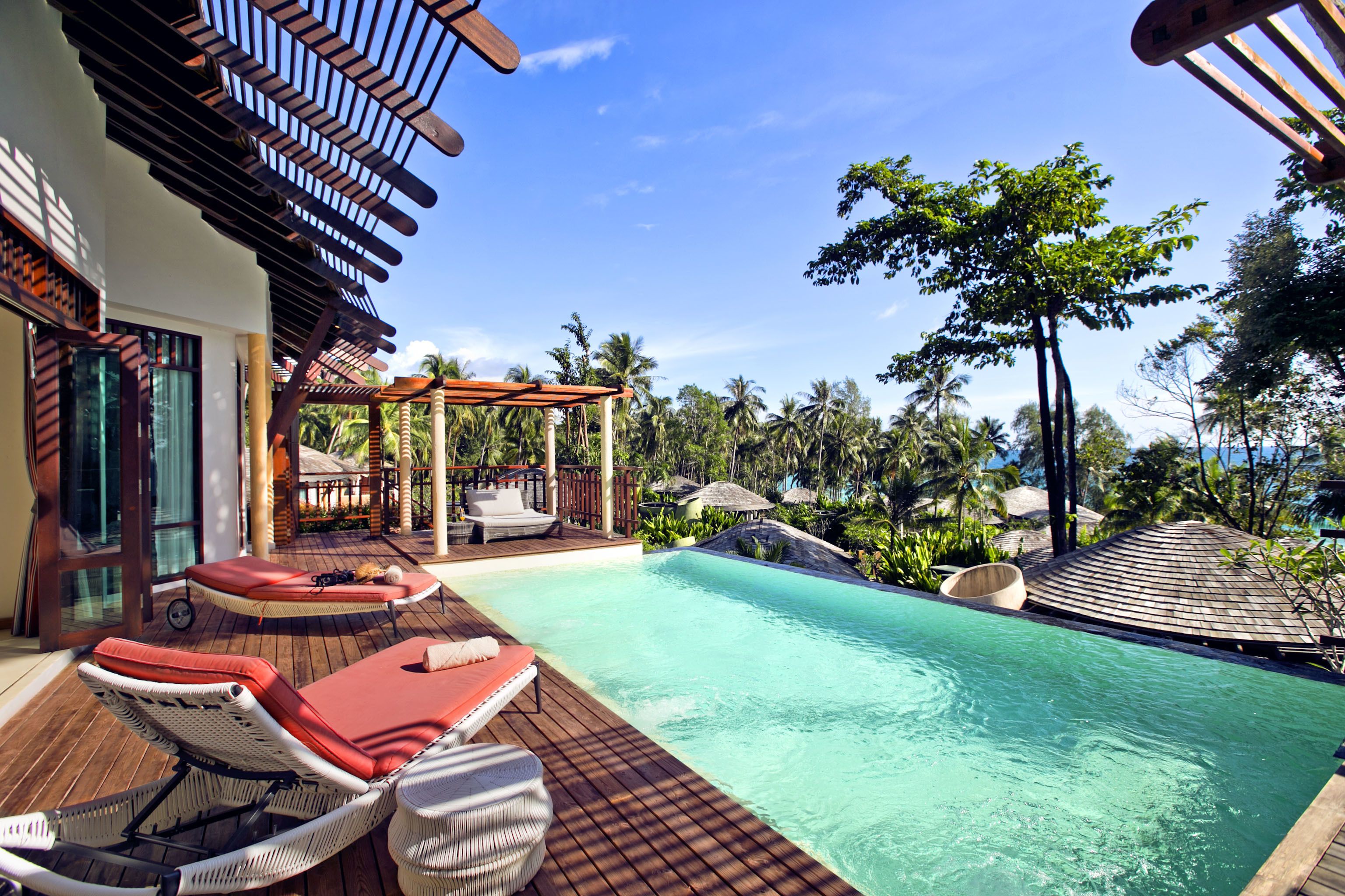 Área de piscina com espreguiçadeiras e deck de madeira.