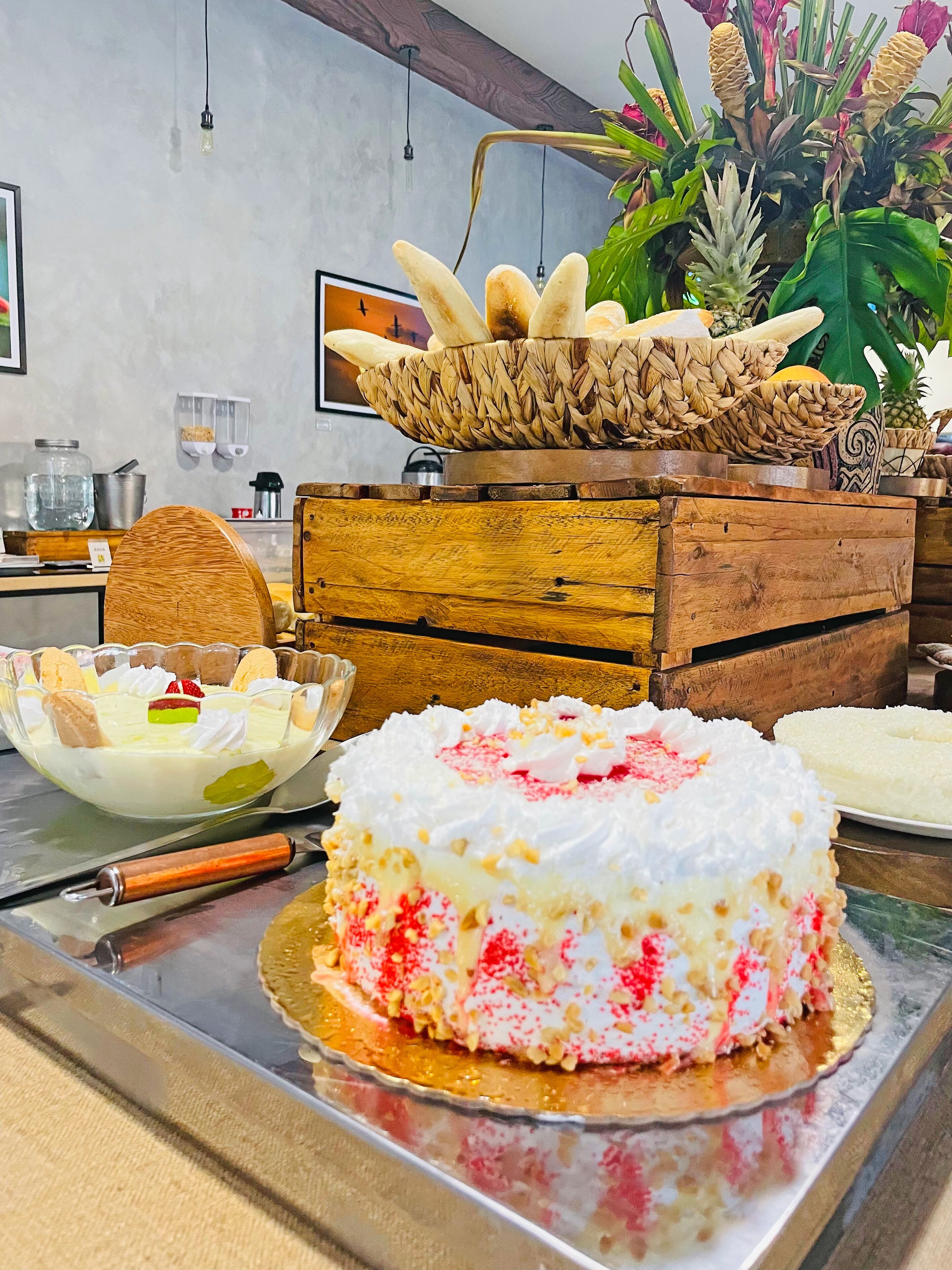Uma mesa de sobremesas com bolo, uma tigela de frutas e uma cesta de vime.