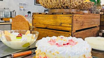 Uma mesa de sobremesas com bolo, uma tigela de frutas e uma cesta de vime.