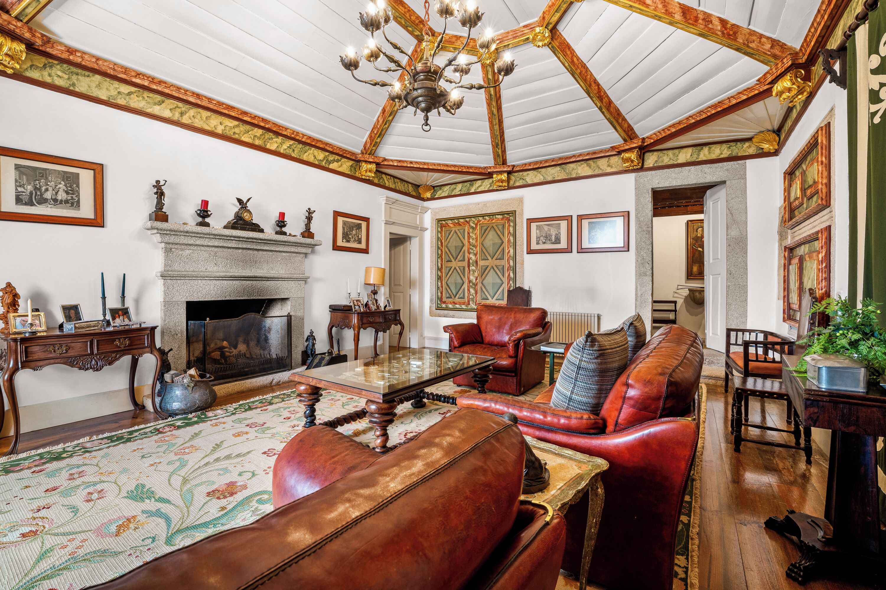 Quarto tradicional com lareira, mobiliário de couro e um candelabro.
