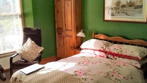 Quarto com cama, cadeira, guarda-roupa e janela com persianas.