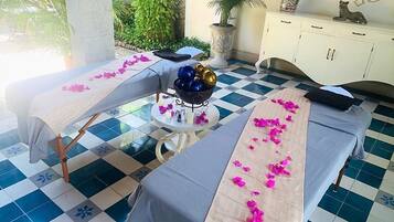 Sala de spa com duas macas de massagem, uma mesinha com objetos decorativos e um armário com uma figura de raposa.