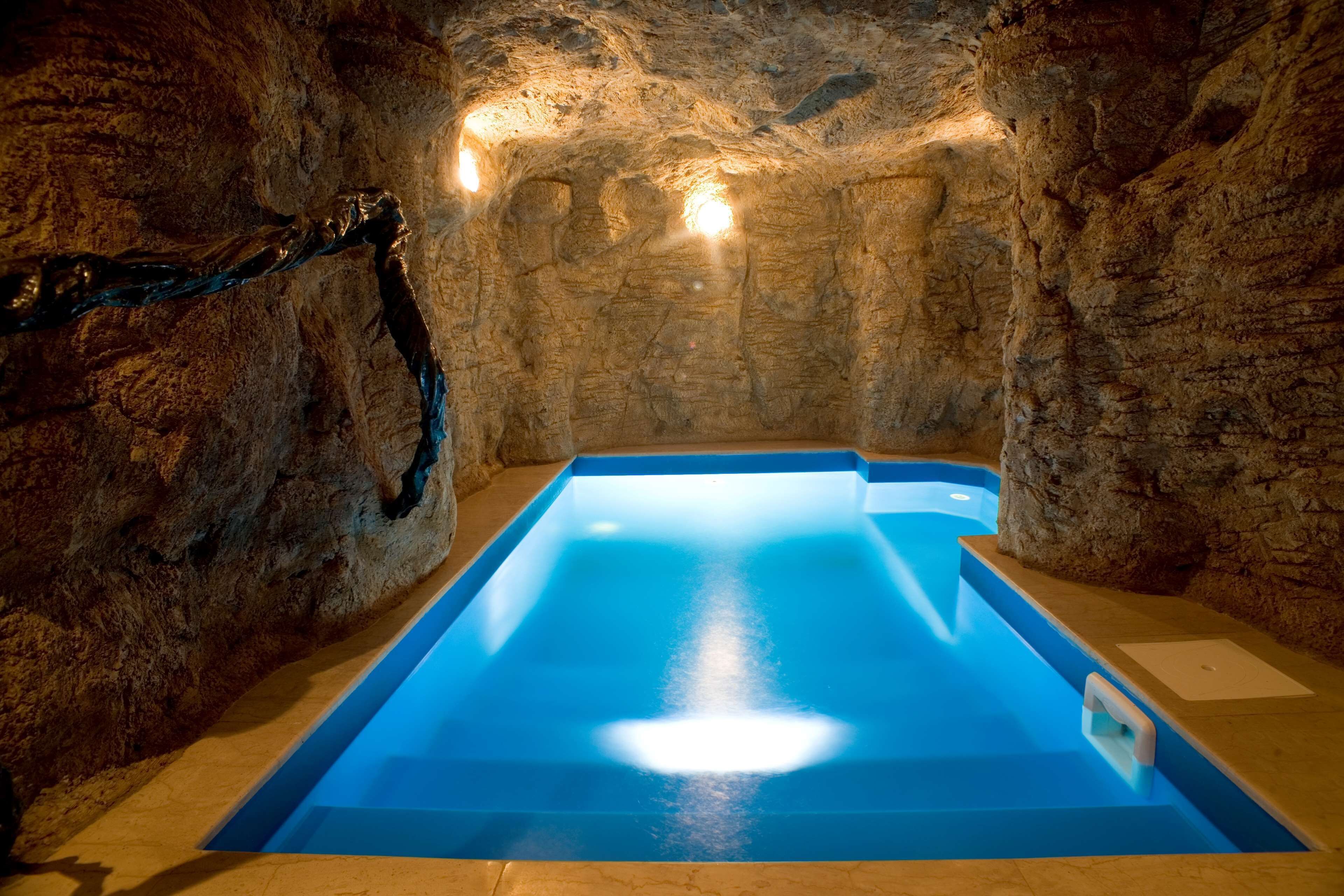 Uma piscina spa com interior azul, rodeada por paredes de rocha natural.