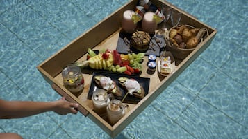 Uma bandeja com comida e bebidas ao lado de uma piscina.