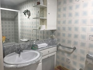 Casa de banho com lavatório, espelho e porta-toalhas.