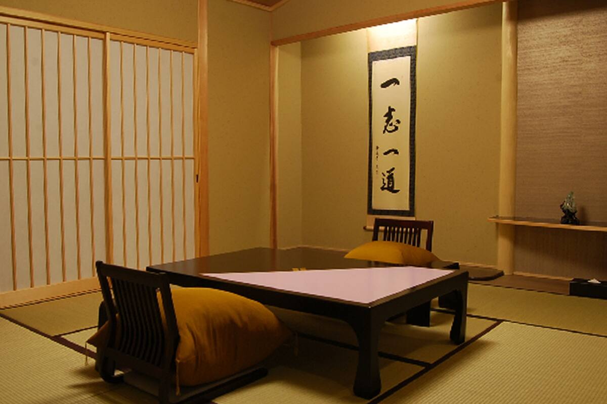 Um quarto japonês tradicional com tatames, uma mesa baixa com almofadas e uma porta deslizante.