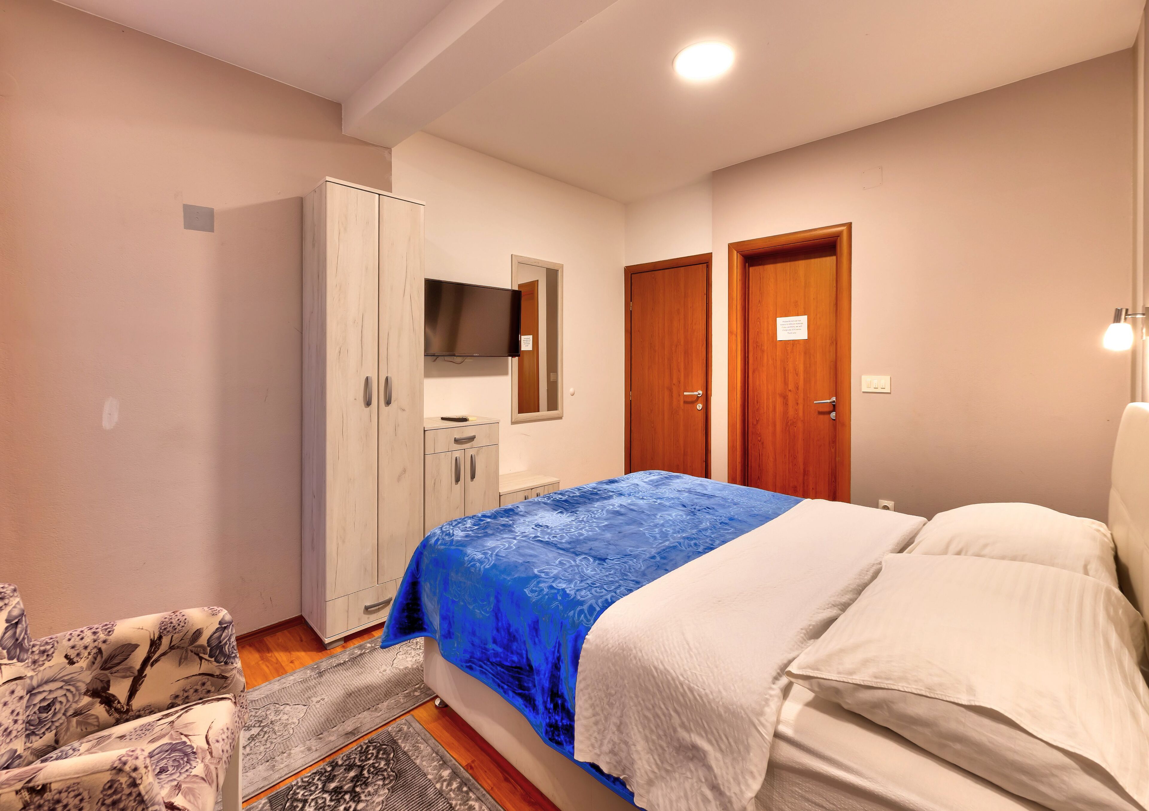 Quarto com cama, guarda-roupa, televisão e porta.