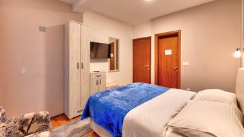 Quarto com cama, guarda-roupa, televisão e porta.