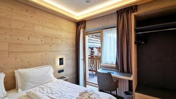 Quarto com painéis de madeira, uma cama, uma escrivaninha e uma cadeira.