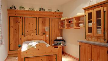 Um quarto de madeira com cama, mesa de cabeceira, cadeira de massagem e um armário com portas de vidro.