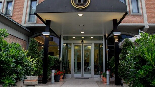 Entrada de hotel com porta de vidro, toldo preto e placa com o número 20.