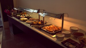 Buffet com diversas opções de comida, incluindo frutas, doces e acompanhamentos.