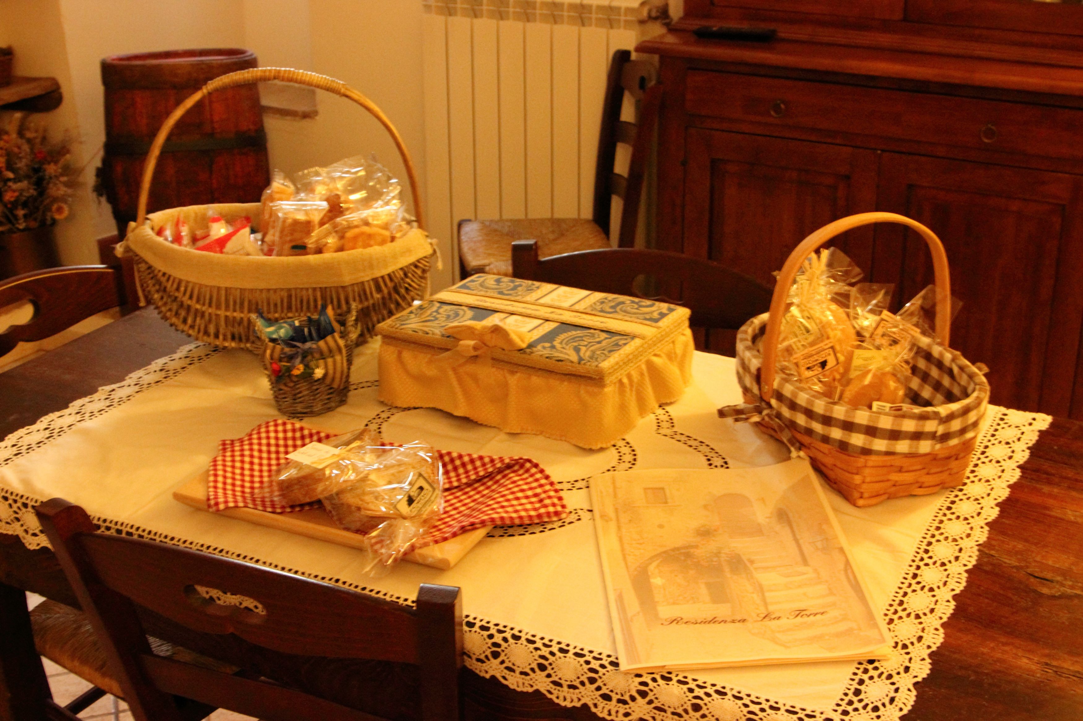 Uma mesa de jantar com toalha rendada, um cesto de pão, um cesto de vime, uma caixa de madeira e um guardanapo dobrado.