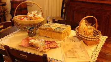 Uma mesa de jantar com toalha rendada, um cesto de pão, um cesto de vime, uma caixa de madeira e um guardanapo dobrado.