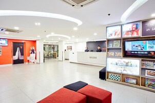 Um hall de hotel moderno, com balcão de recepção, área de estar e painéis digitais.