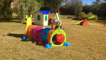 Uma criança brincando em uma estrutura de recreação colorida em um parque.