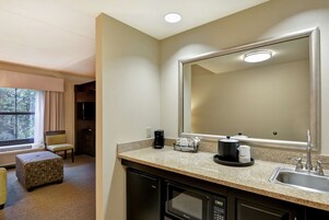 Casa de banho de hotel com um espelho grande, lavatório, máquina de café e micro-ondas.