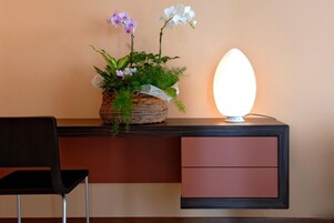 Uma mesa com uma planta em vaso e uma luminária moderna.