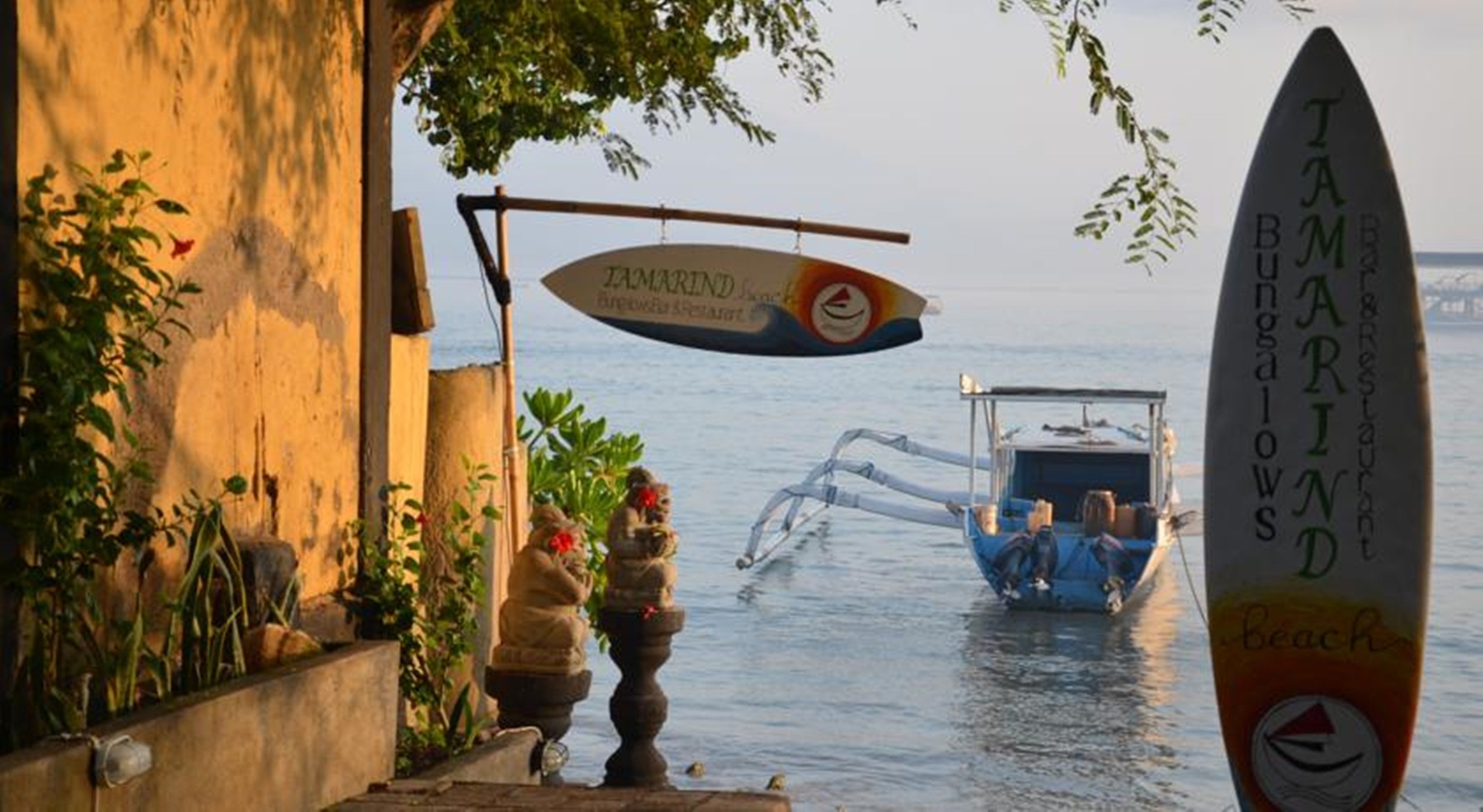 Restaurante à beira-mar chamado 'Jamarind Bungalows Beach' com um barco atracado nas proximidades.