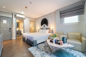 Quarto de hotel com uma cama, um sofá, uma mesinha com um vaso de flores e uma janela com vista.