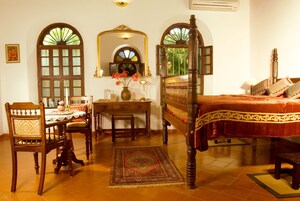 Um quarto tradicional com uma cama de dossel, uma escrivaninha de madeira com cadeira, e uma mesa de jantar com cadeiras.