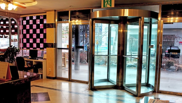 Um saguão de hotel com balcão de recepção, um elevador de vidro e vista para o exterior.