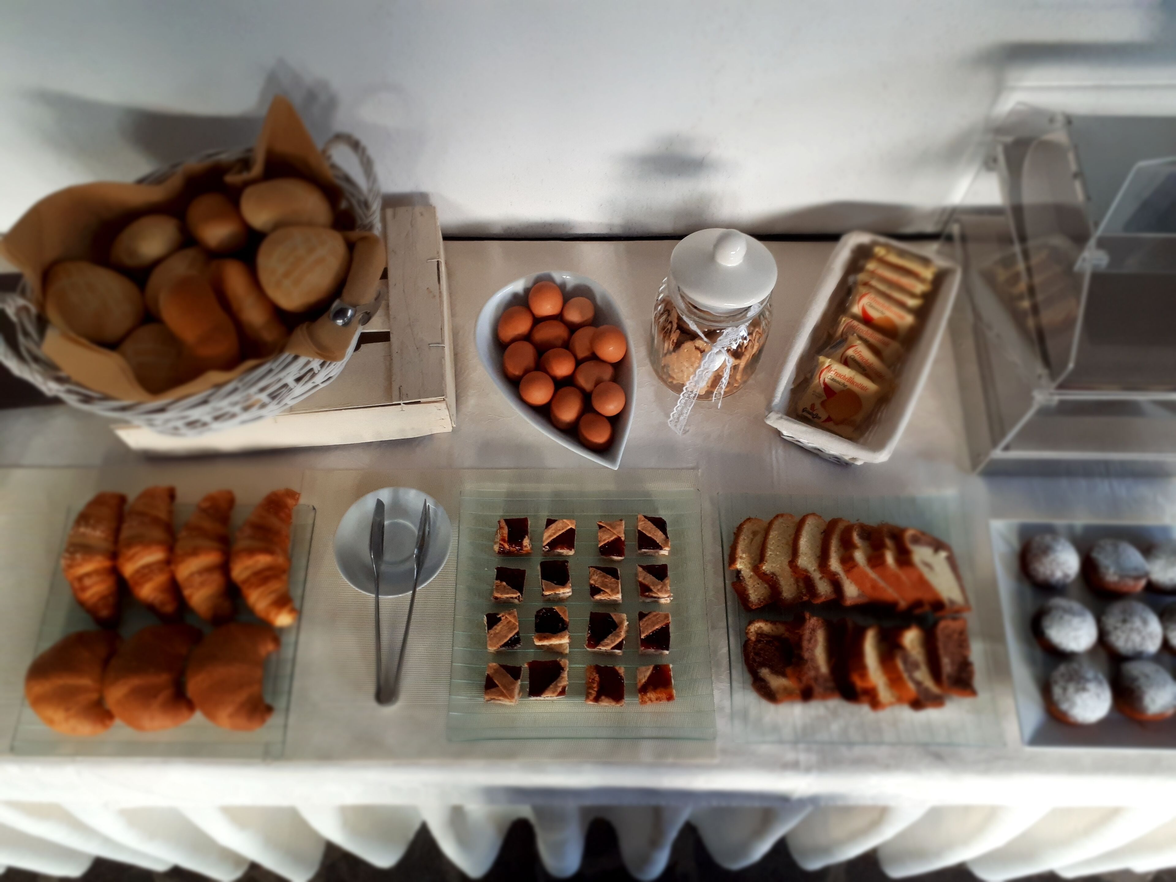 Buffet com diversos produtos de panificação, incluindo croissants, doces e sobremesas.