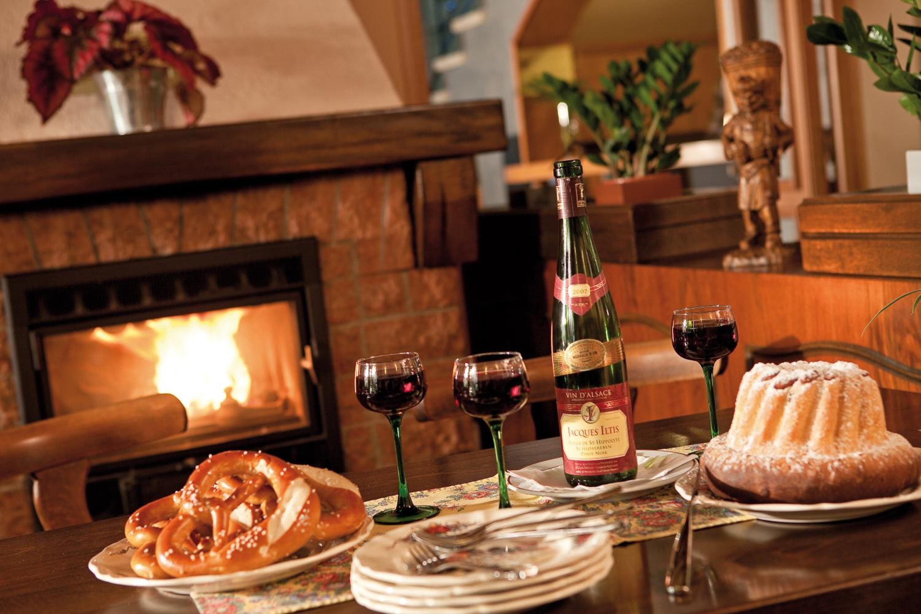 Mesa posta com uma garrafa de vinho, copos, pretzels e um bolo bundt.