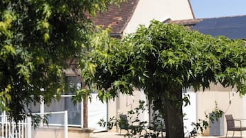 Uma casa com telhado inclinado, uma árvore no jardim da frente e uma cerca branca.