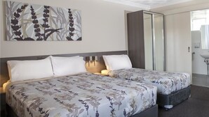 Quarto de hotel com duas camas, um espelho grande e uma obra de arte floral na parede.