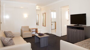 Sala moderna com sofá, poltrona, mesa de centro e televisão de tela plana em um móvel.