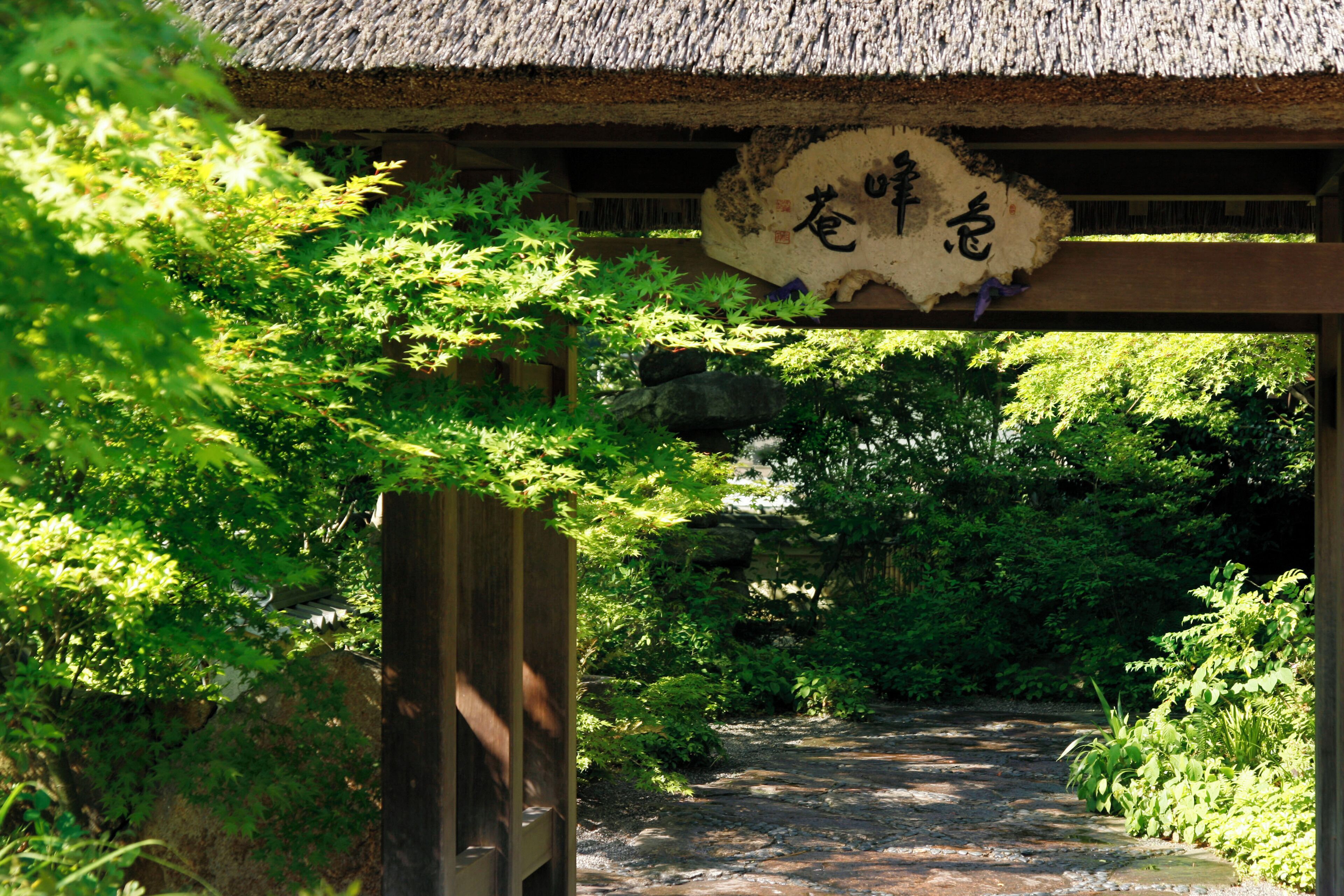 Um edifício japonês tradicional com telhado de palha e estrutura de madeira em primeiro plano.