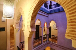 Um pátio com arcos, uma escadaria e uma varanda com corrimão.
